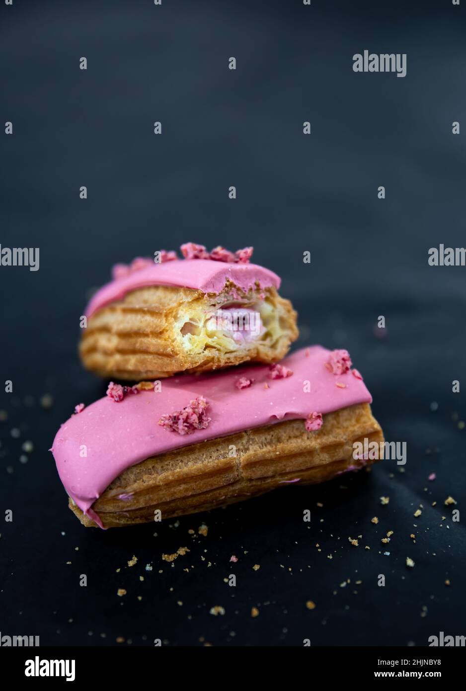 Close-up of a cut berry eclair on a black background Stock Photo - Alamy
