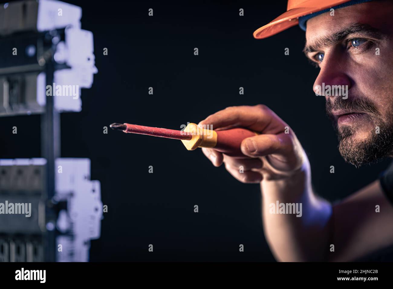 A male electrician works in a switchboard with an electrical connecting ...