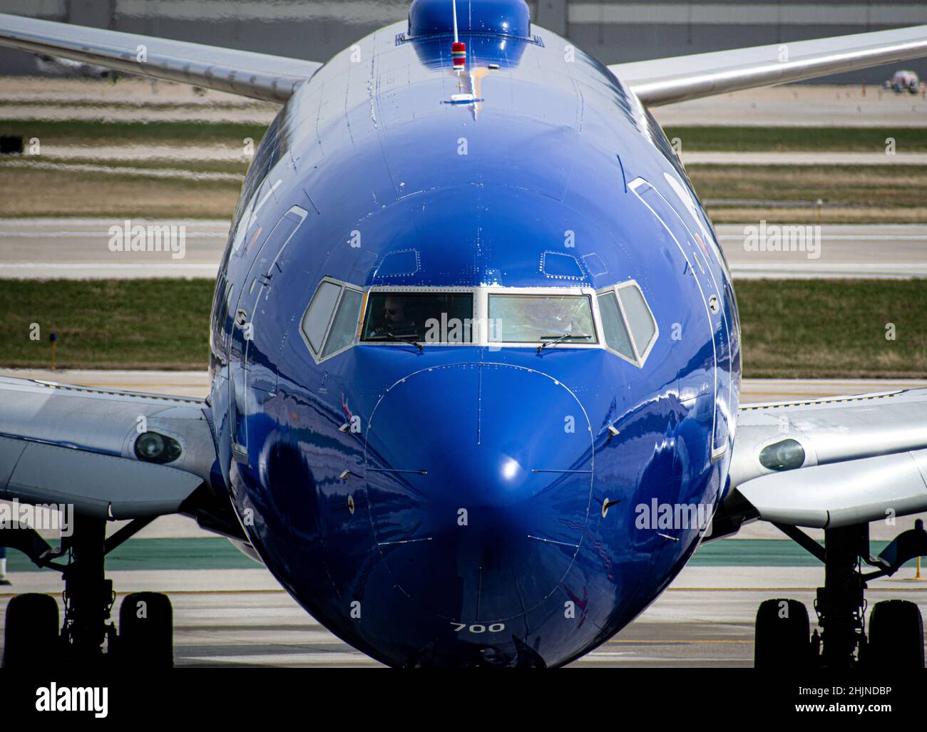 Closeup of the front of a modern blue plane at an airport under the ...
