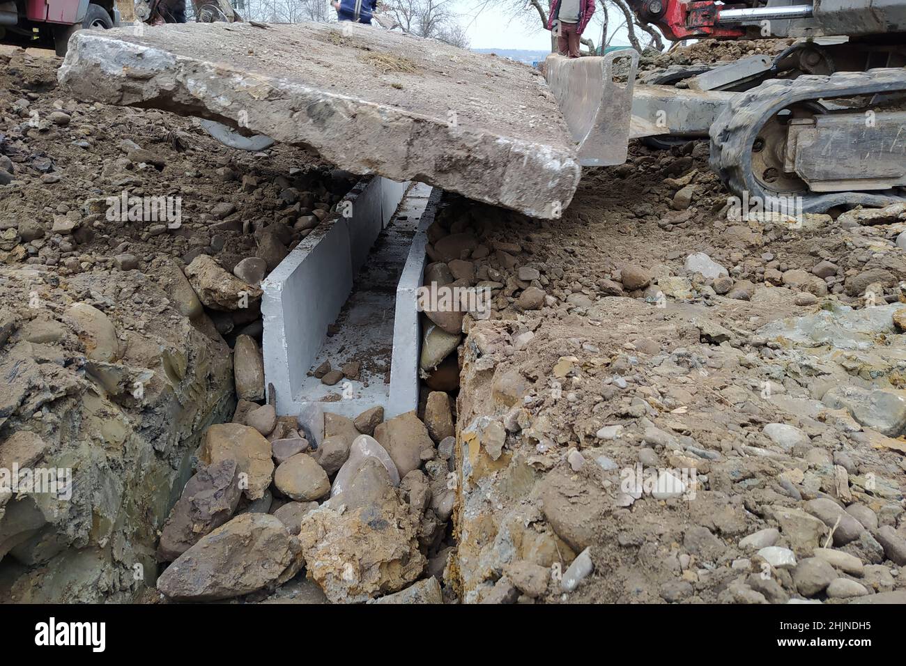The excavator installs concrete trays for drainage of rainwater in ...