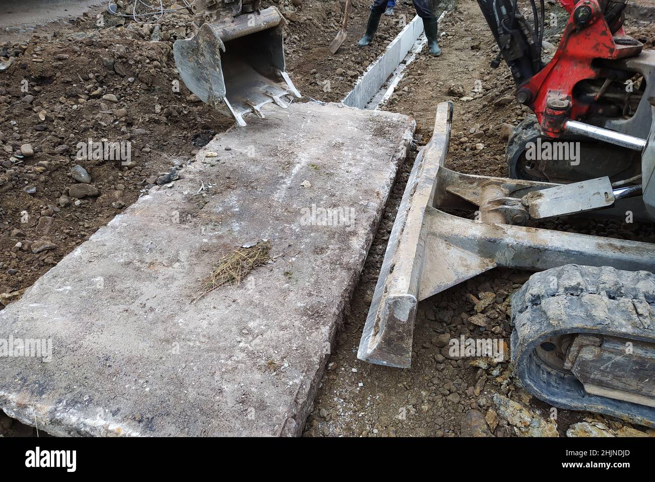 The excavator puts concrete slabs for moving through the gutter ...