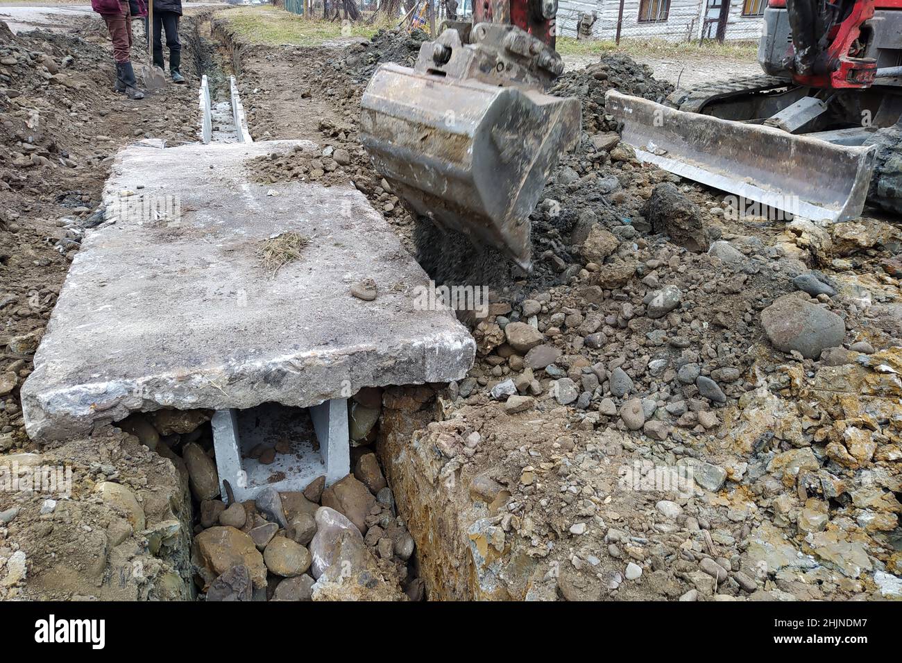 The excavator puts concrete slabs for moving through the gutter ...