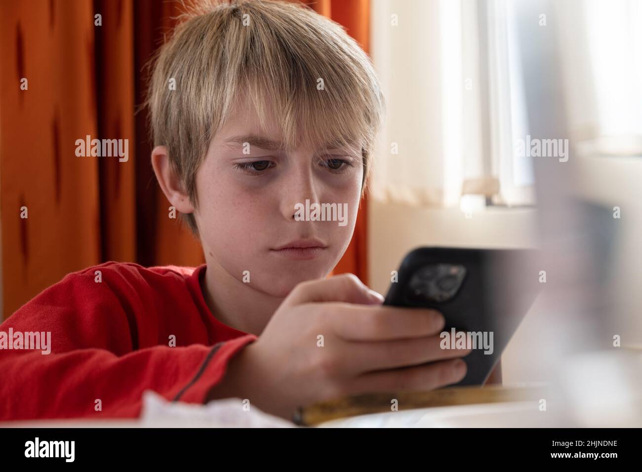 Kid looking at smartphone during breakfast Stock Photo - Alamy