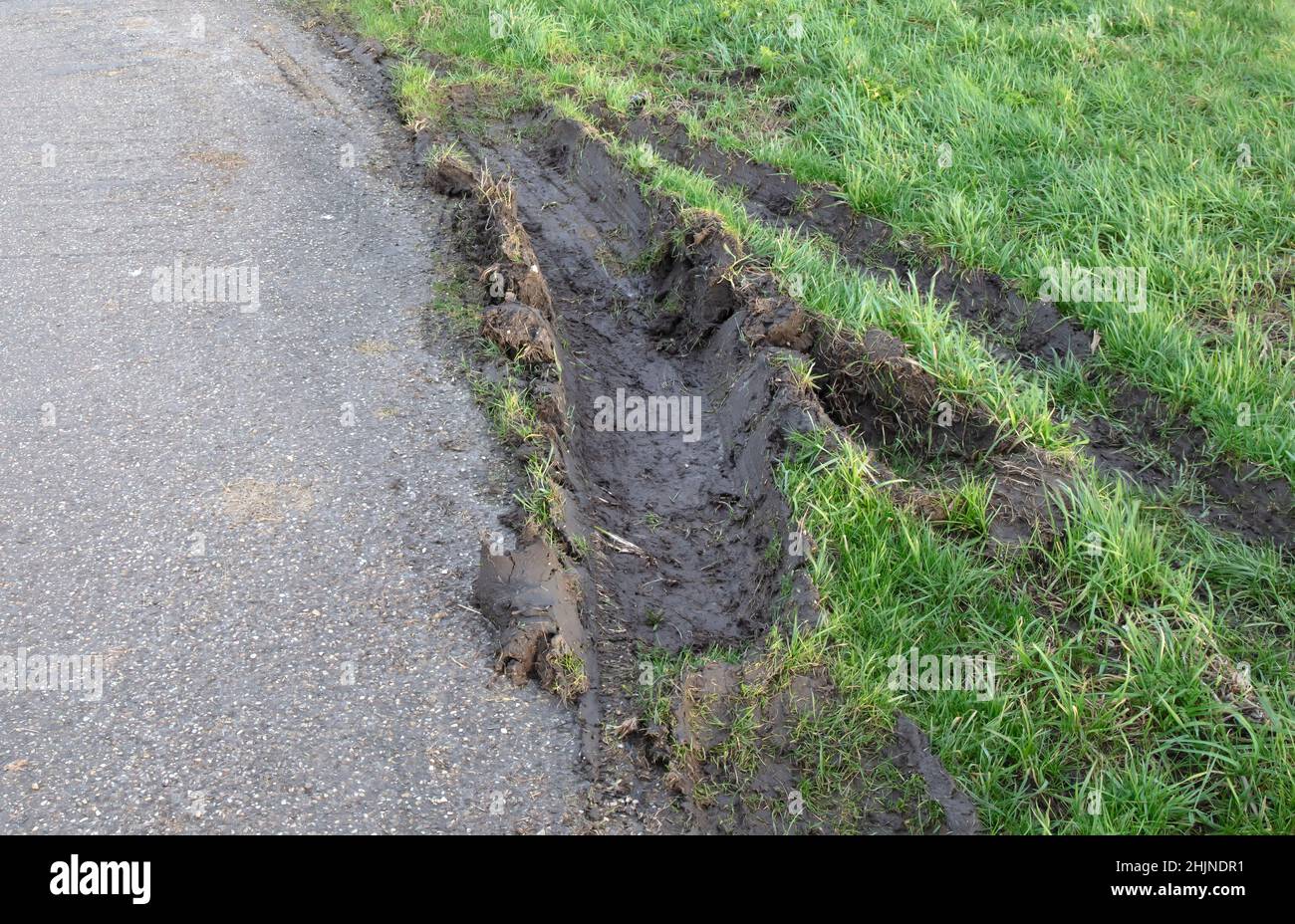 Closeup view of car wheel tracks traces in mud next to asphalt road ...