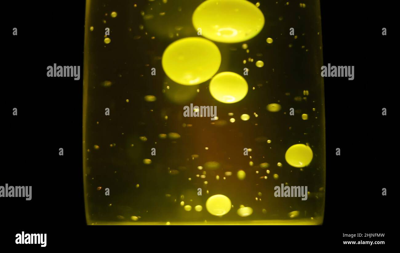 Colorful lava lamp balls moving slowly. Yellow lava lamp with bubbles ...