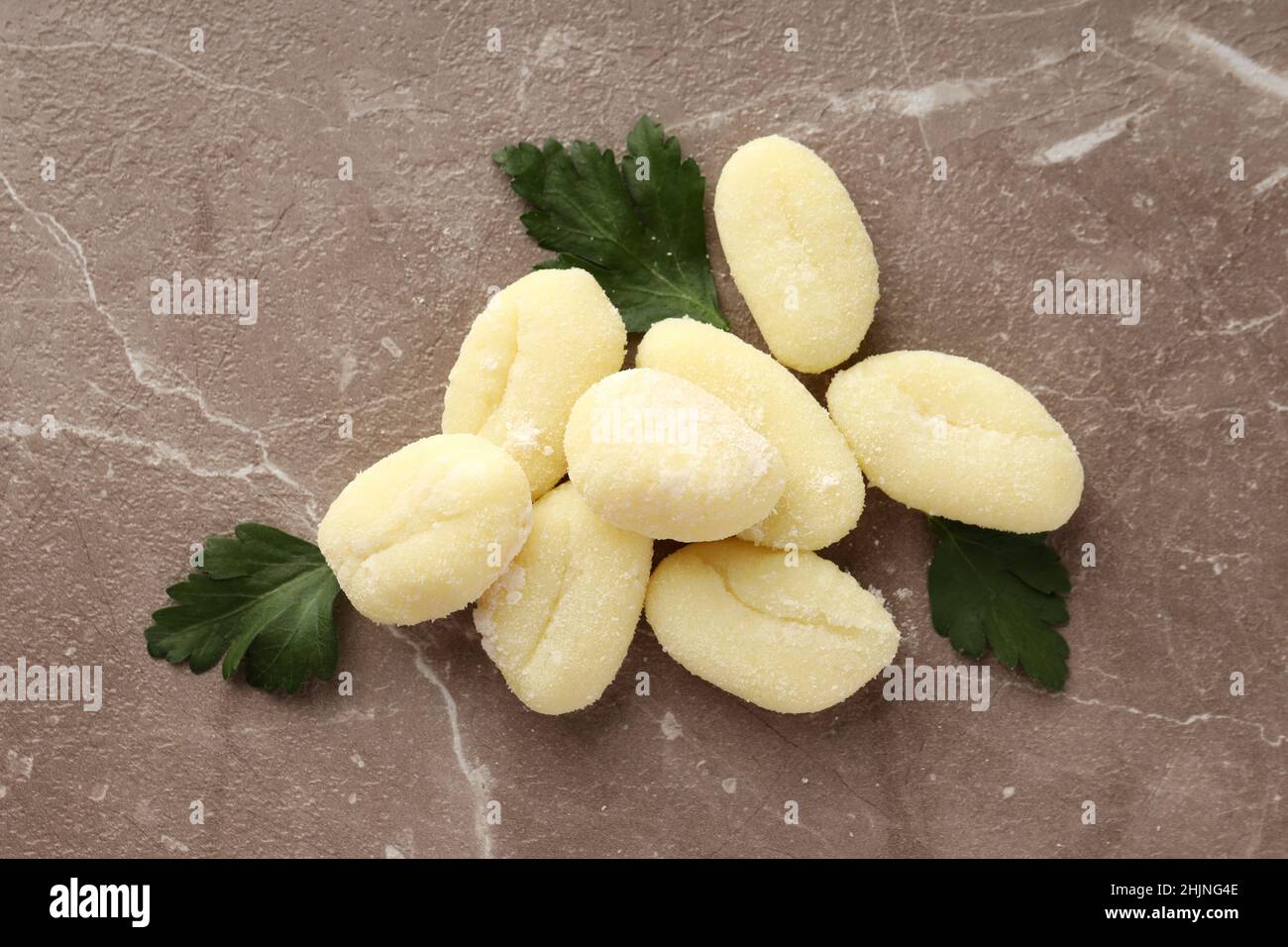 Raw potato gnocchi with parsley on gray textured background Stock Photo ...