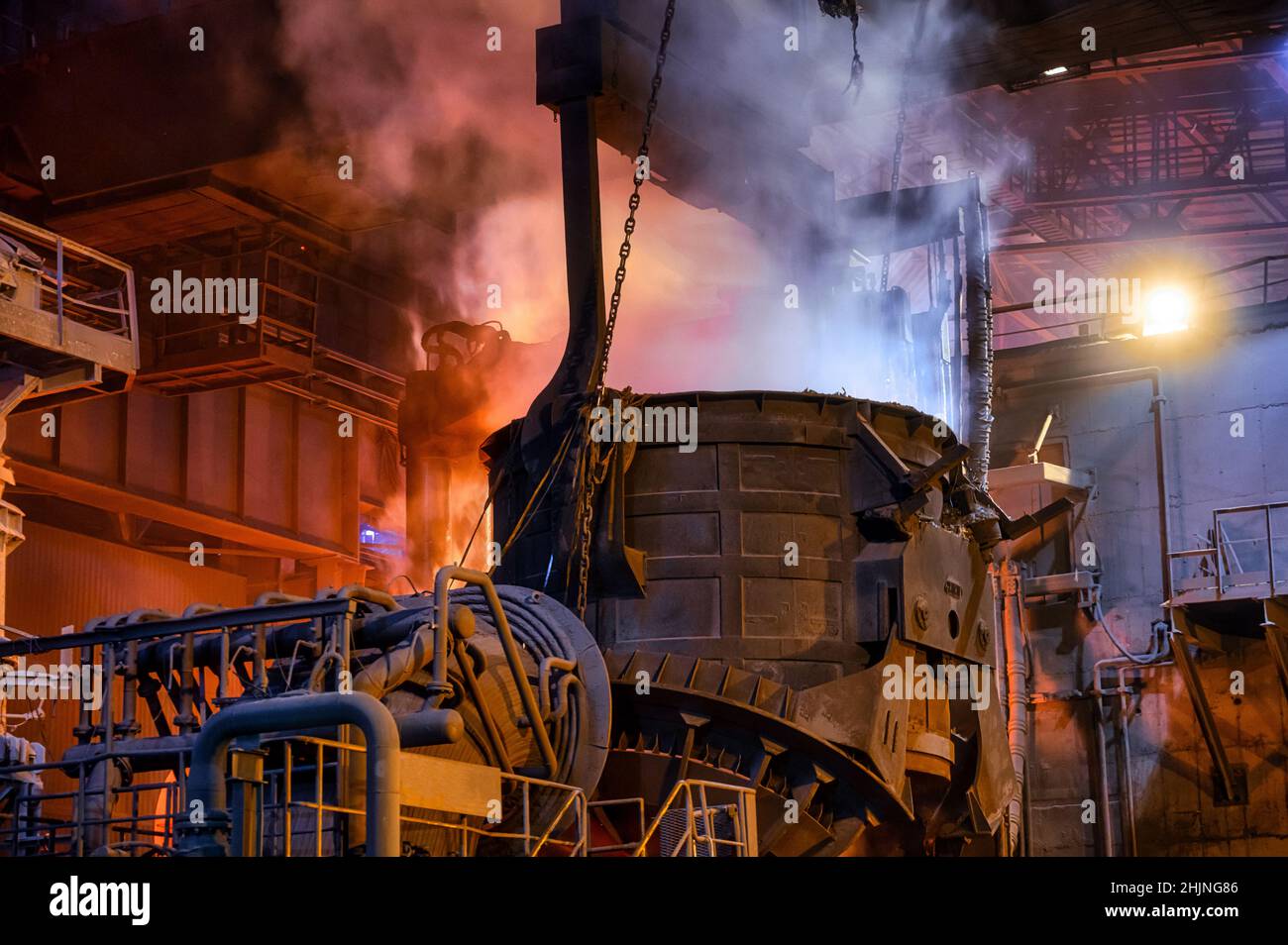 A metallurgical ladle filled with molten metal bucket is suspended on a ...