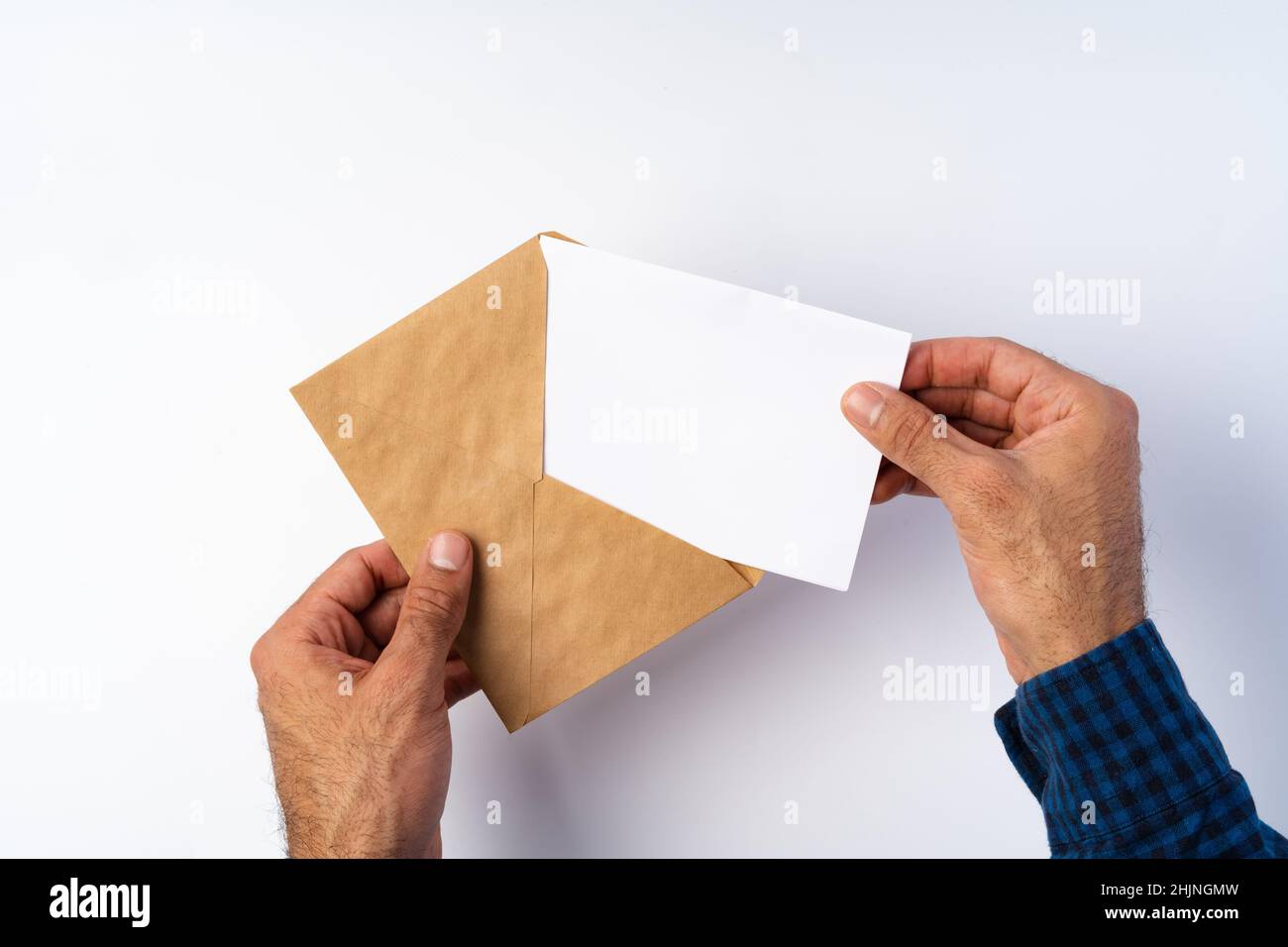 Top view of male hands hold (open) an envelope above white background ...