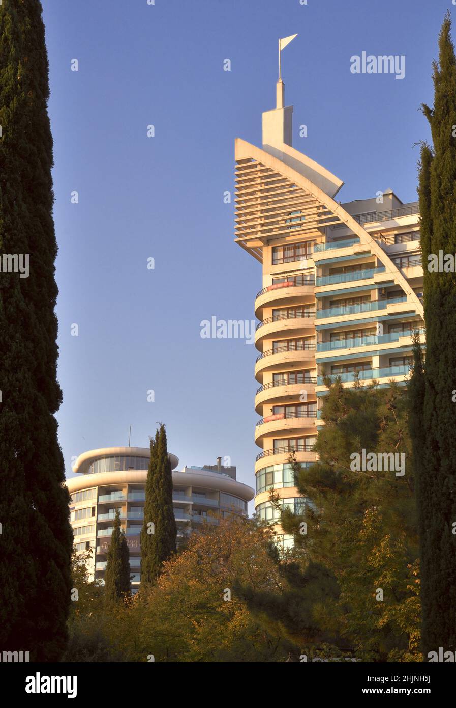 A tall building of modern architecture with a spire, balconies behind ...