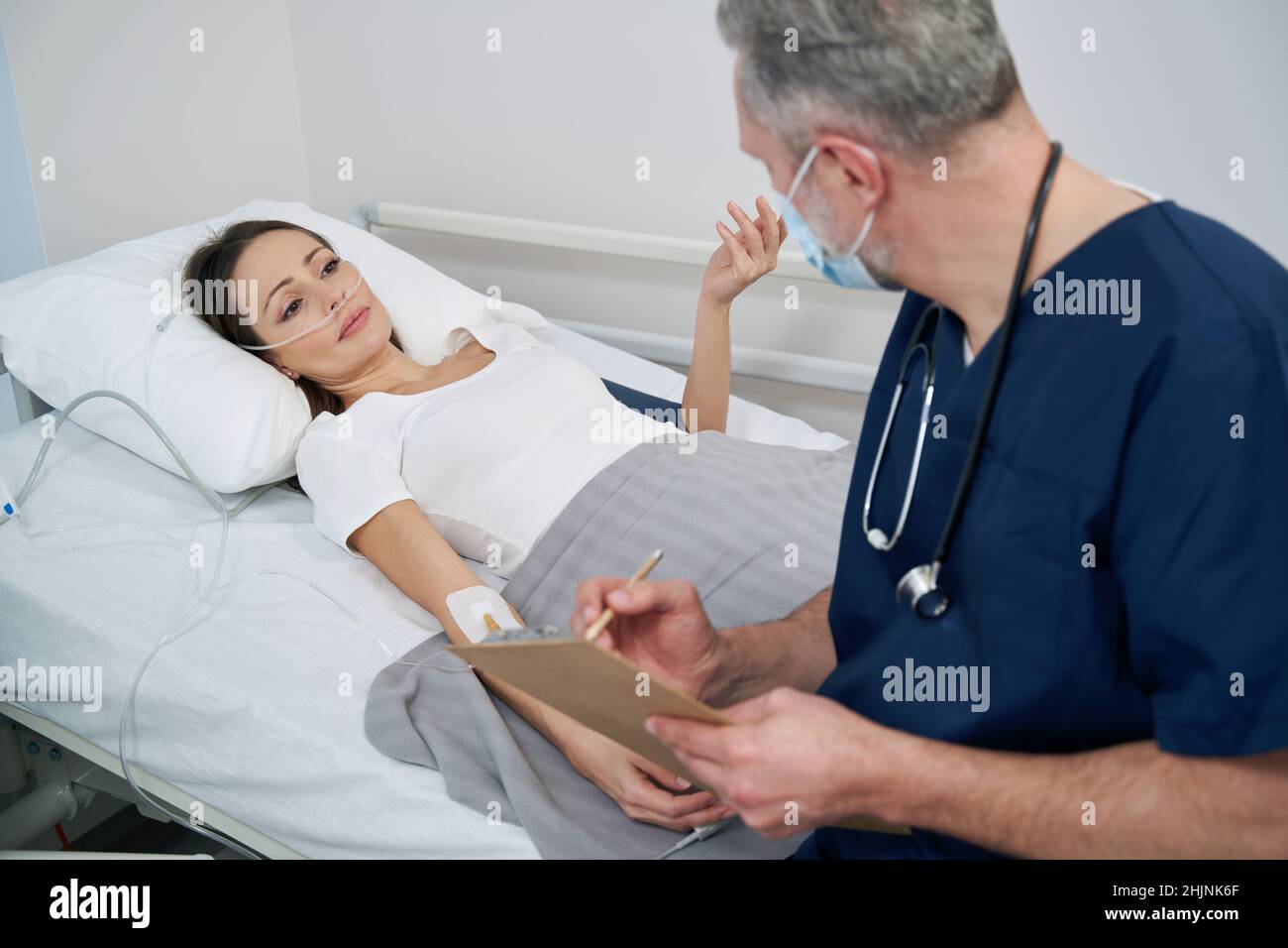 Attending doctor communicating with female patient during ward round ...