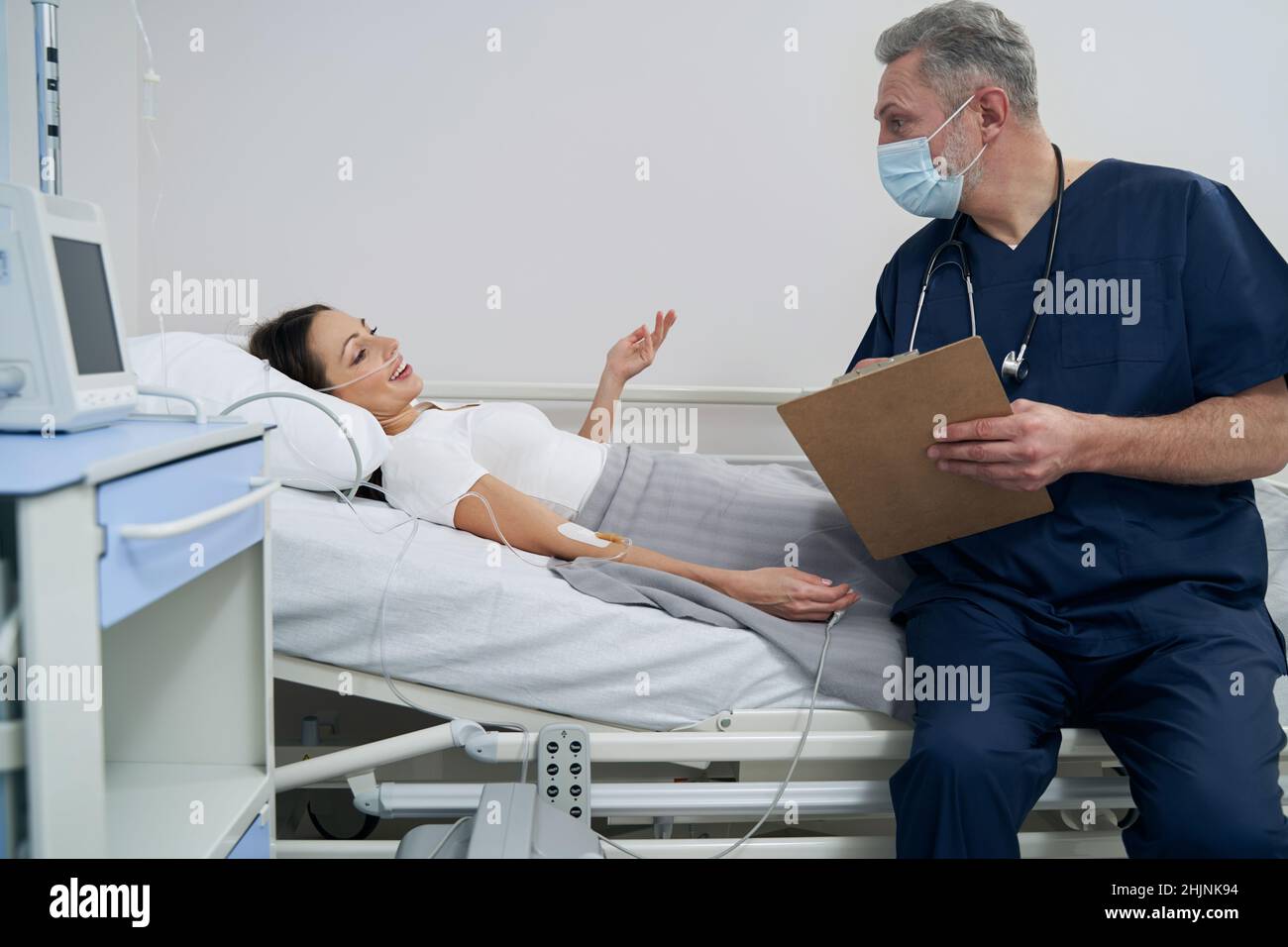 Joyous female patient communicating with doctor during intravenous ...