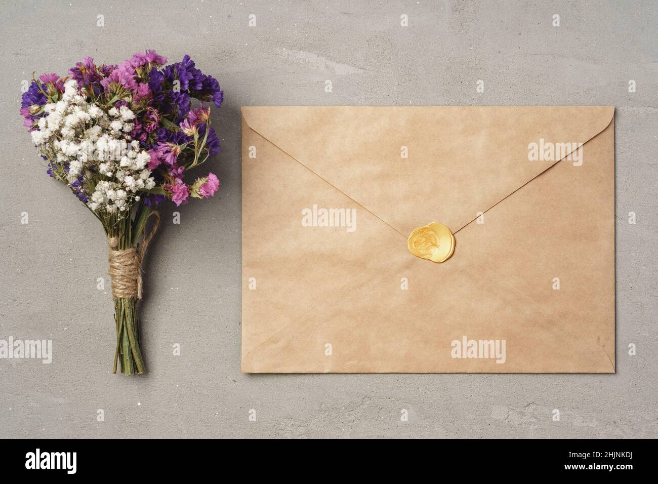 Top view of flower bouquet and craft envelope on gray surface flat lay ...