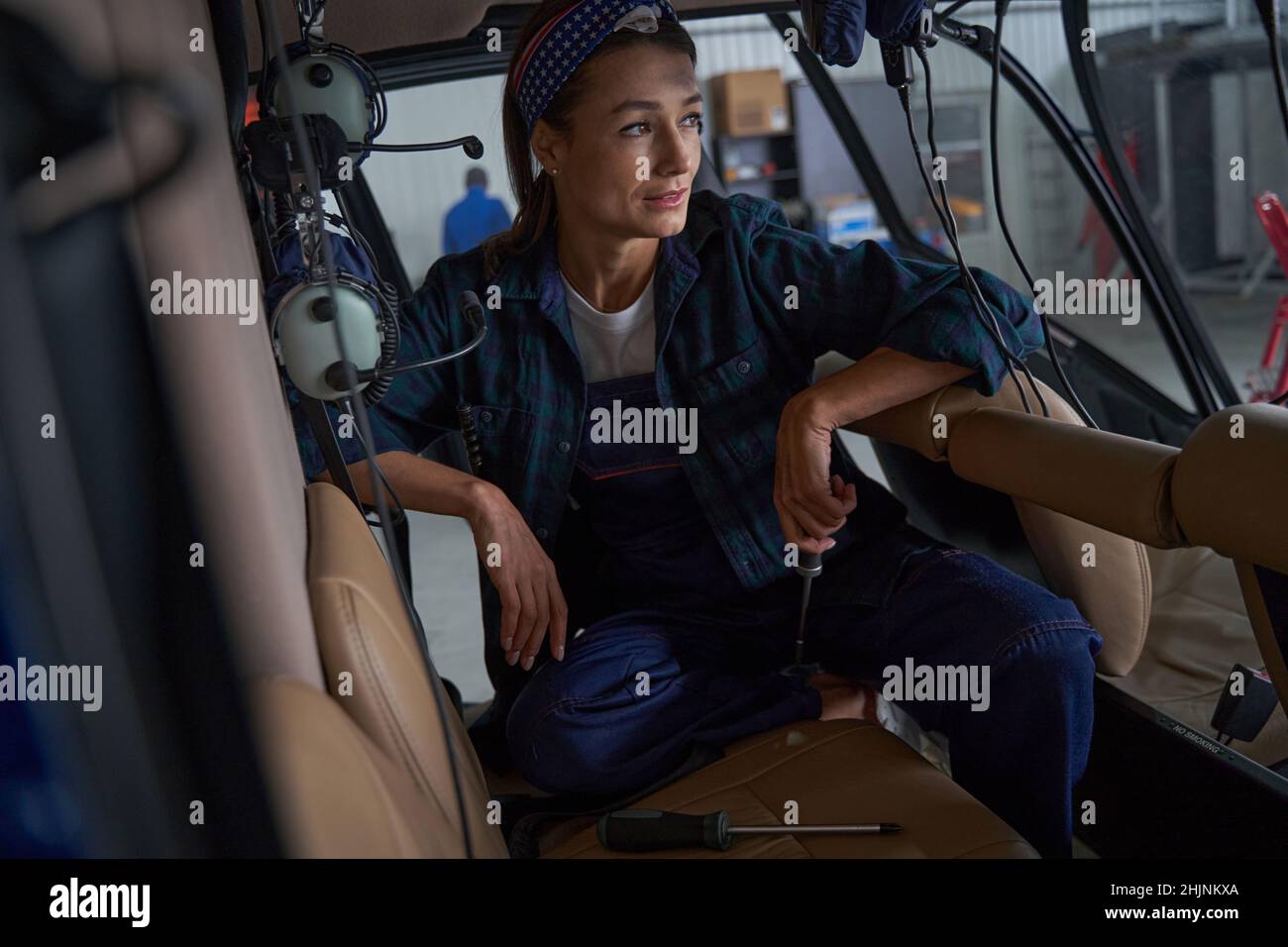 Woman engineer with metal tool in hand sitting in private jet airplane ...
