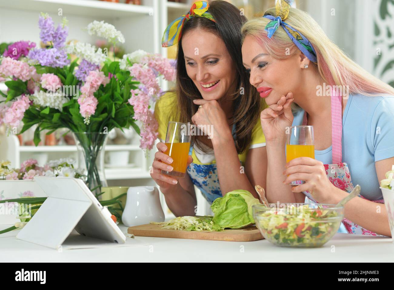 Two beautiful young women cooking together in kitchen Stock Photo - Alamy