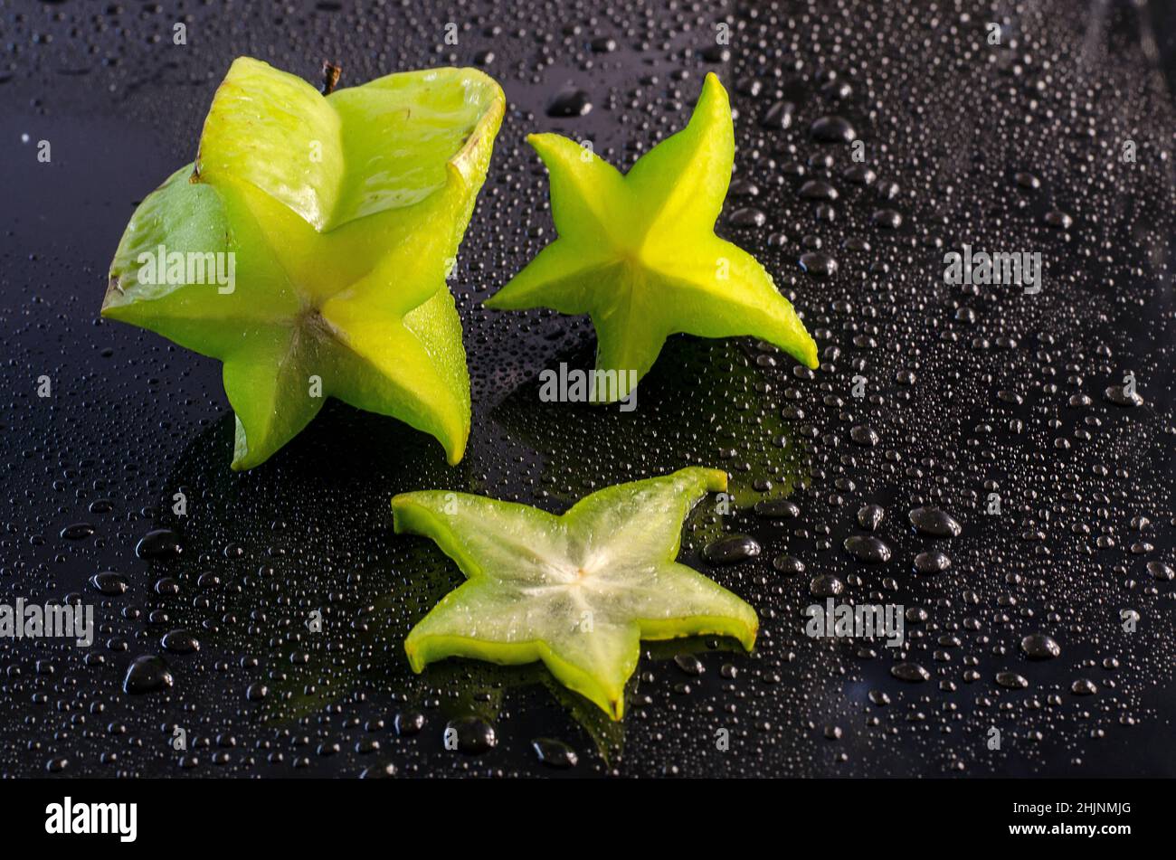 fresh carambola on a black background with drops Stock Photo - Alamy