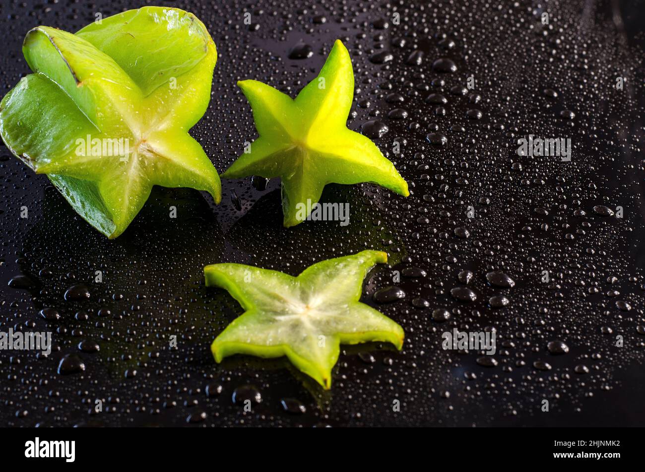 fresh carambola on a black background with drops Stock Photo - Alamy