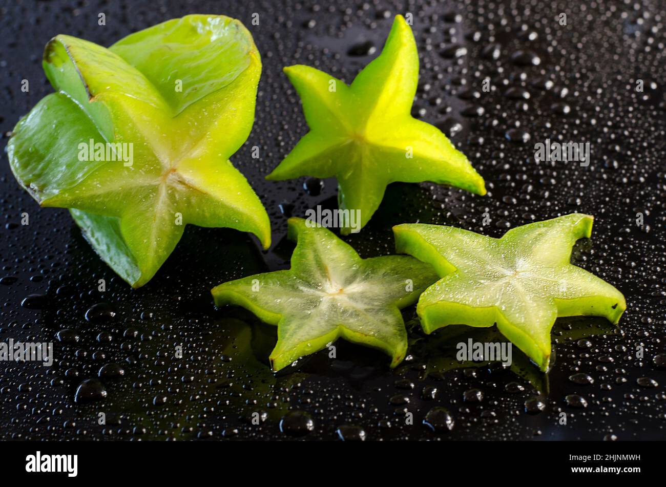 fresh carambola on a black background with drops Stock Photo - Alamy