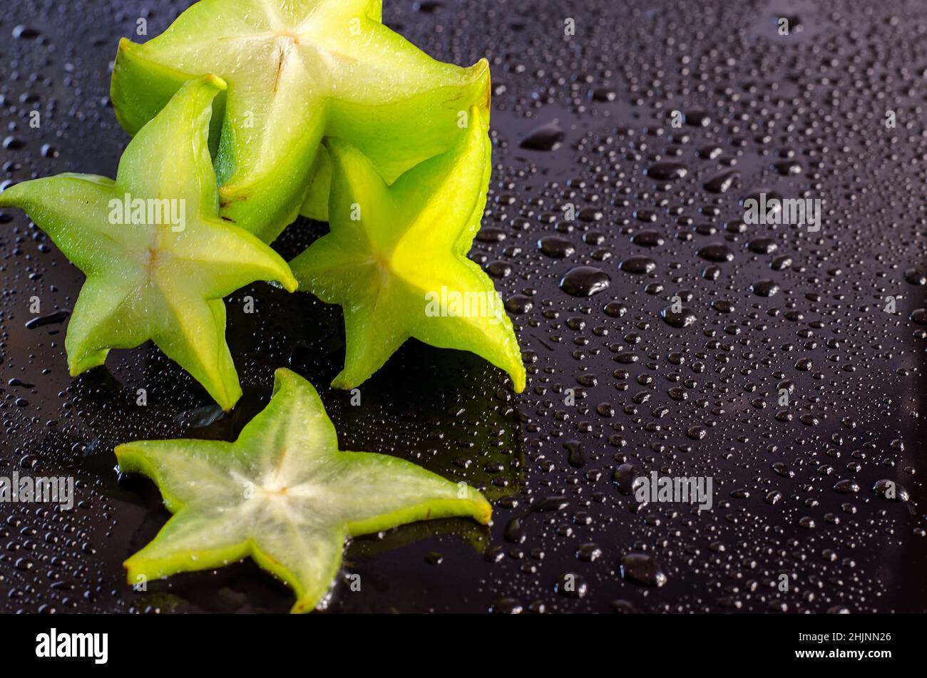fresh carambola on a black background with drops Stock Photo - Alamy