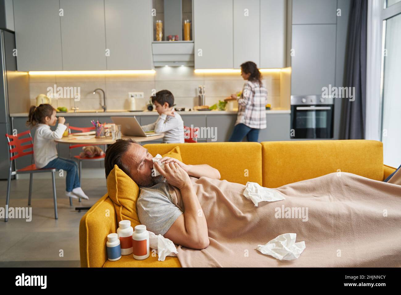 Sick father suffering from cold on kitchen sofa Stock Photo - Alamy