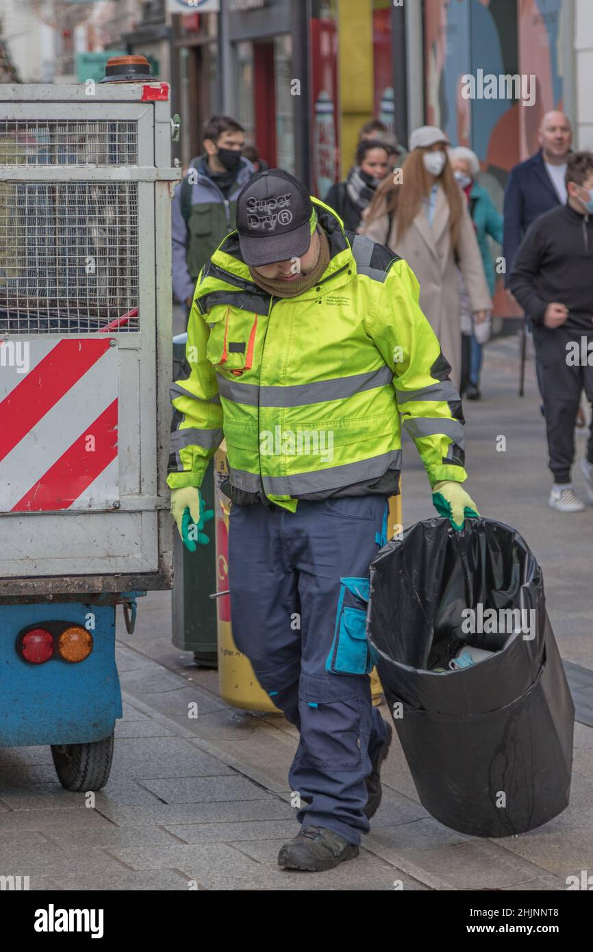 Collecting rubbish from the street, city worker at work carrying a ...