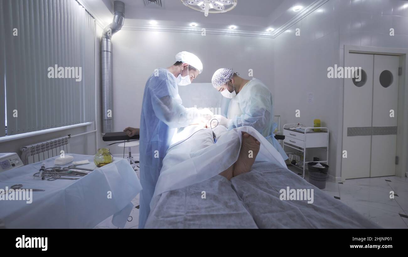 Surgeons team working with the patient who is awake in surgical ...