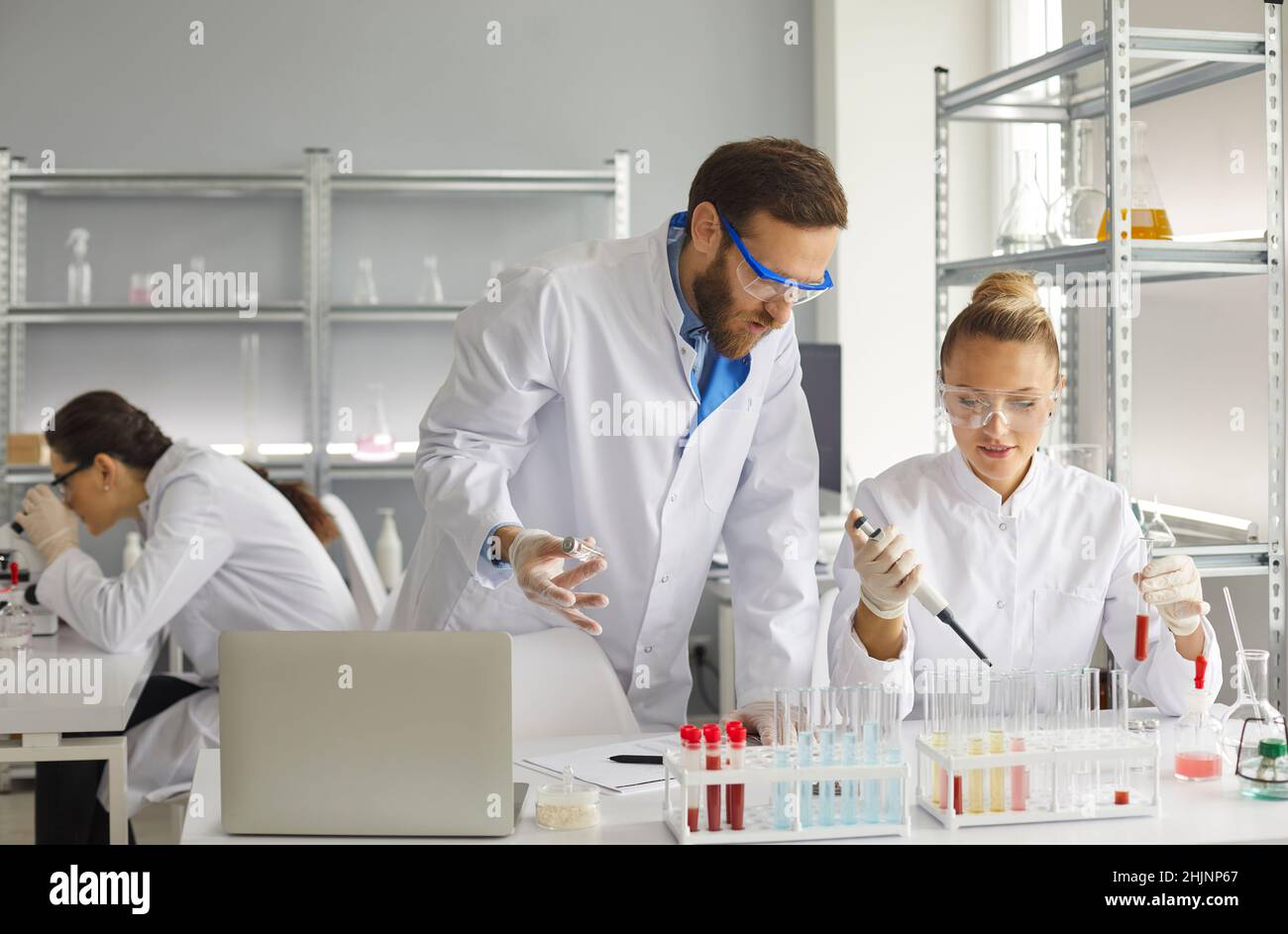 Female and male scientists work together to analyze samples while ...
