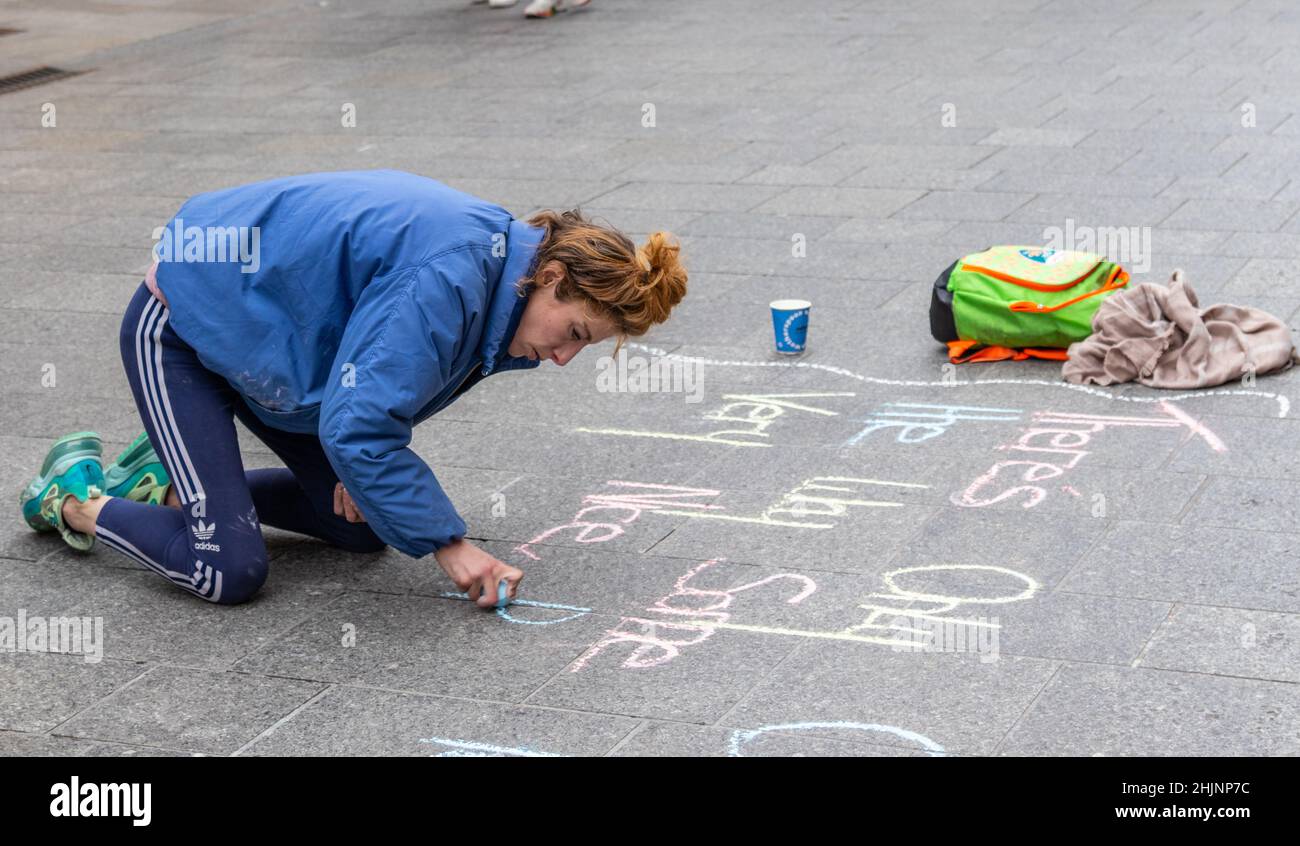 A young woman writes and draws on paving stones, street performance at ...