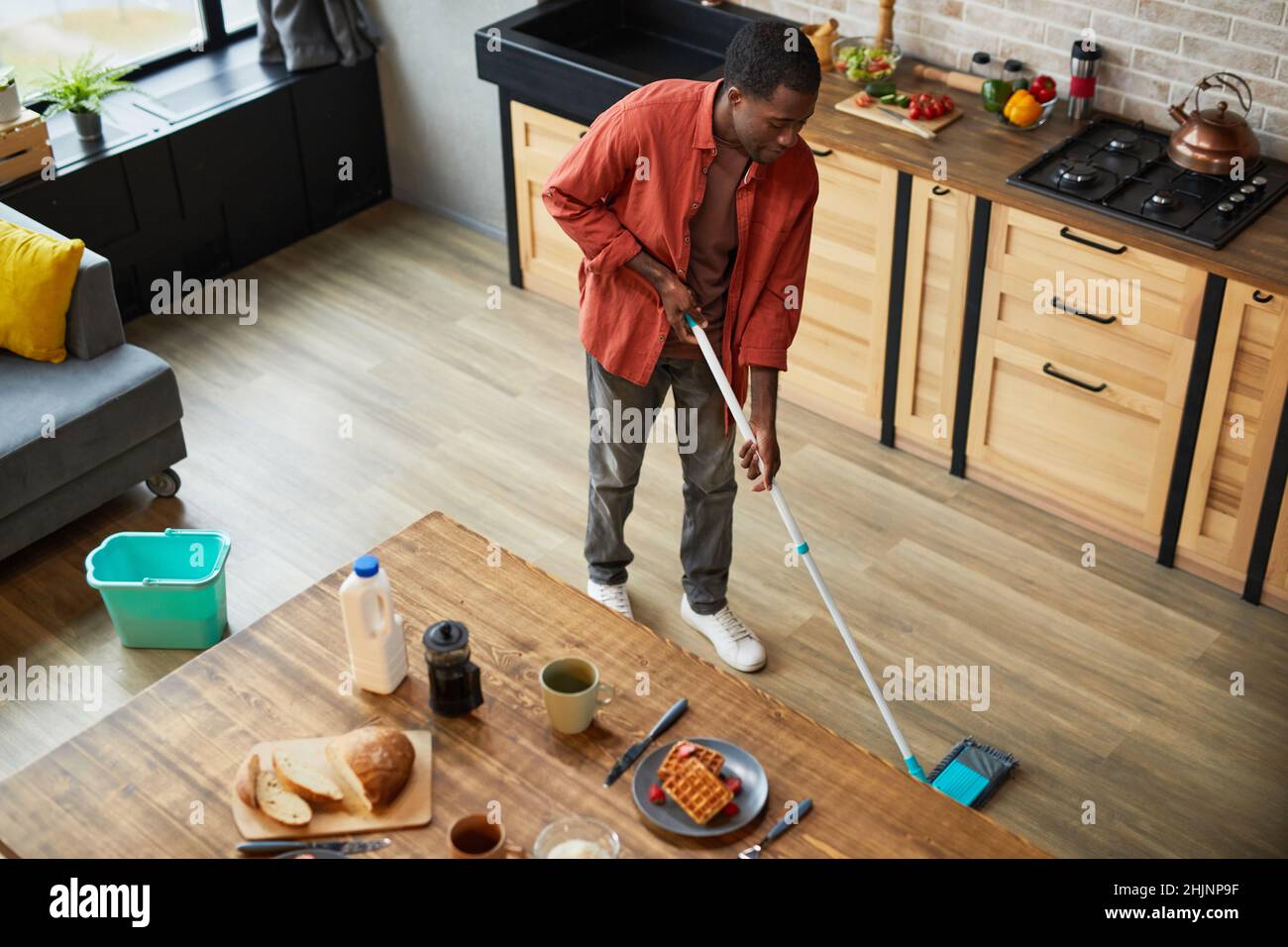 High angle portrait of young African-American man mopping floors while ...