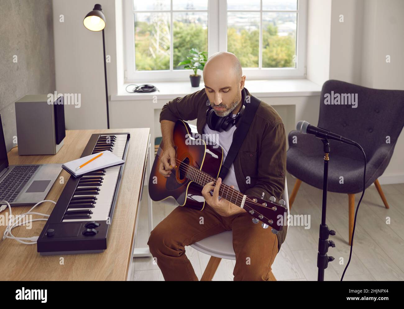 Talented adult male musician plays guitar creating new song in his home ...