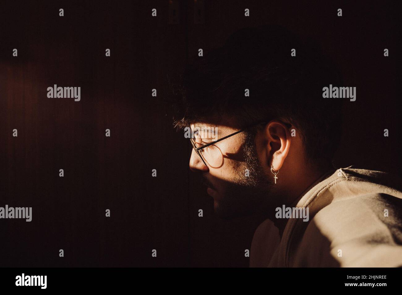 A portrait of a man in eyeglasses with a light reflecting on his face ...