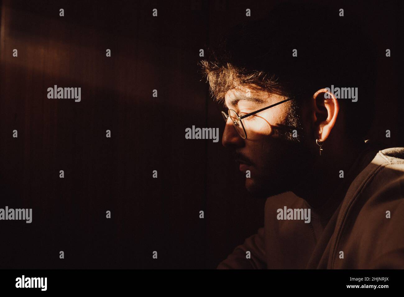 A portrait of a man in eyeglasses with a light reflecting on his face ...