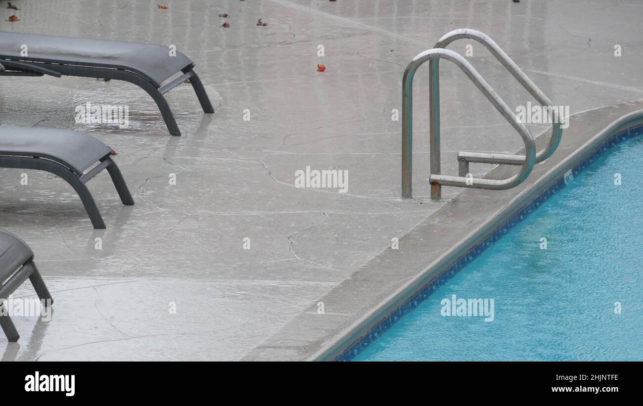 Rain drops falling on water surface of blue swimming pool, rainy day in ...