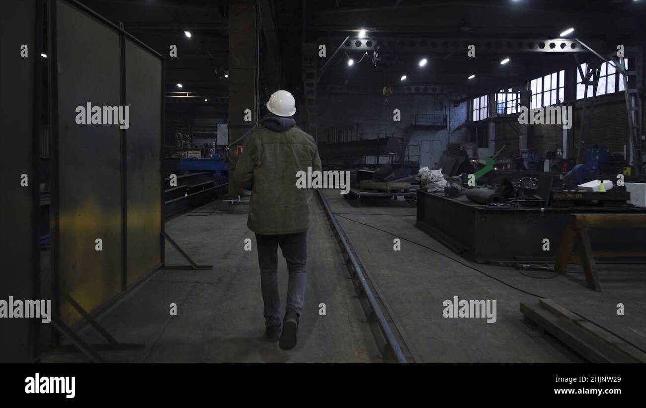 Man walks around factory and looks around. Clip. Foreman oversees work ...