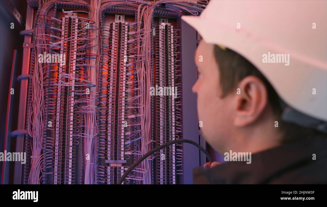 Electric looking at wires. Action. Close-up of man connecting cable to ...