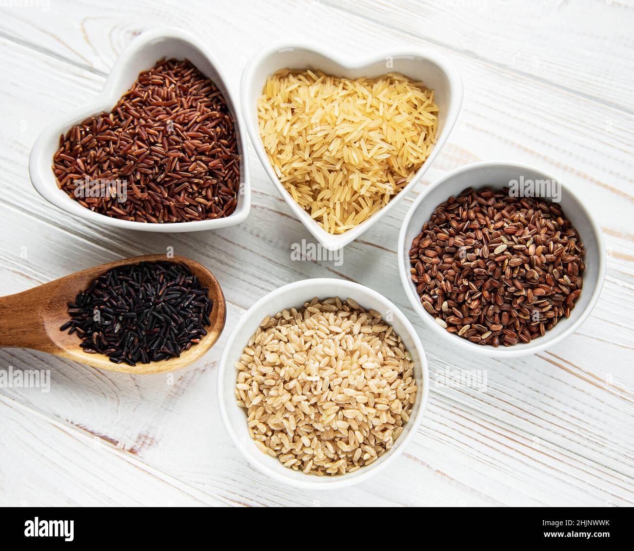 Set of various rice on white wooden background: black, basmati, brown ...