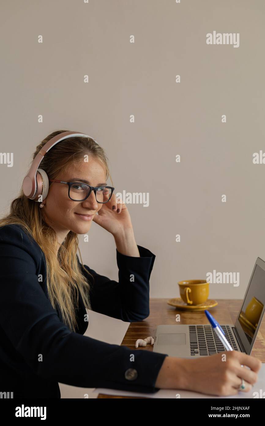 Young woman working at home with laptop and papers on desk and ...
