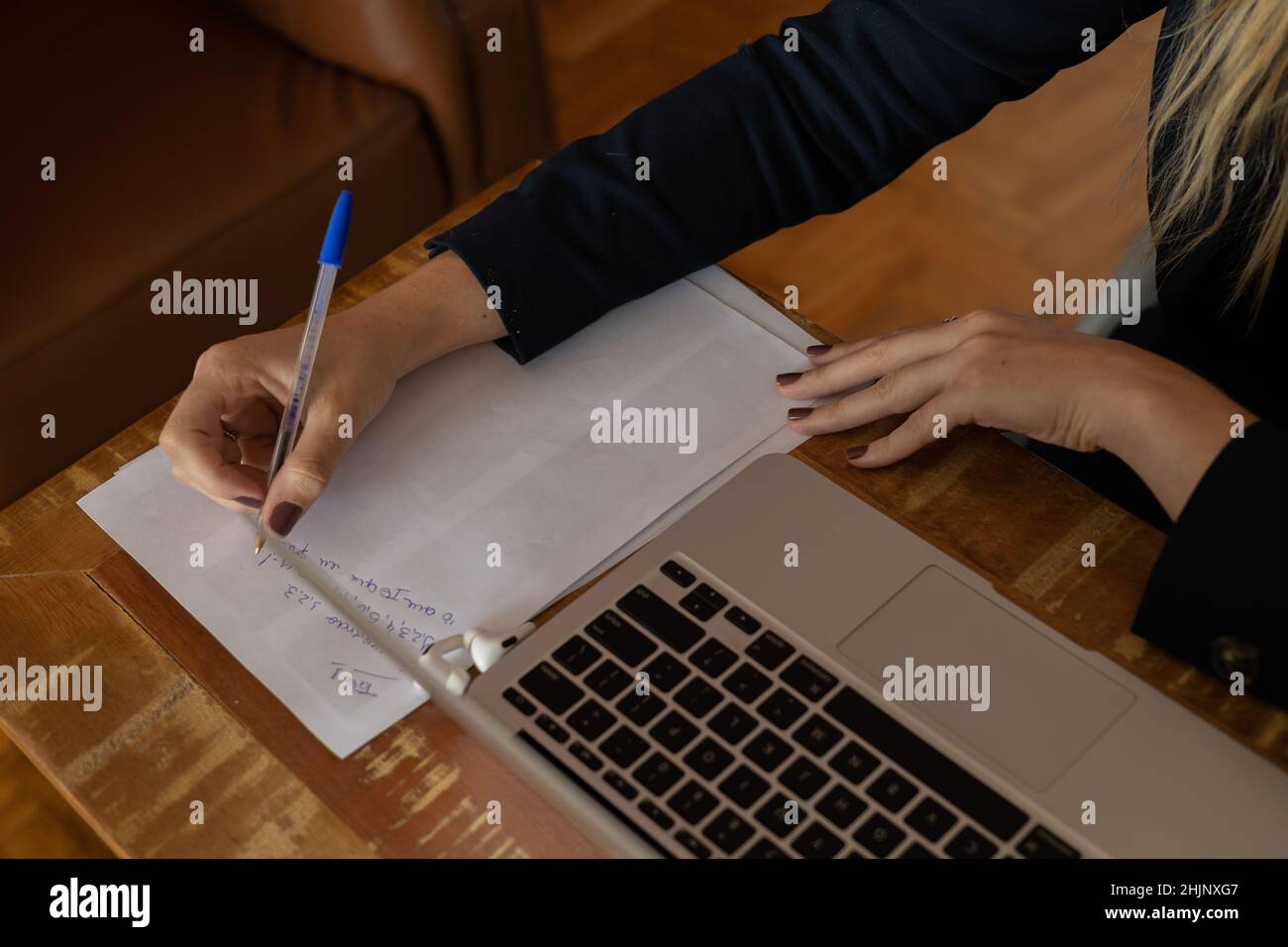 Young woman working at home with laptop and papers on desk and ...