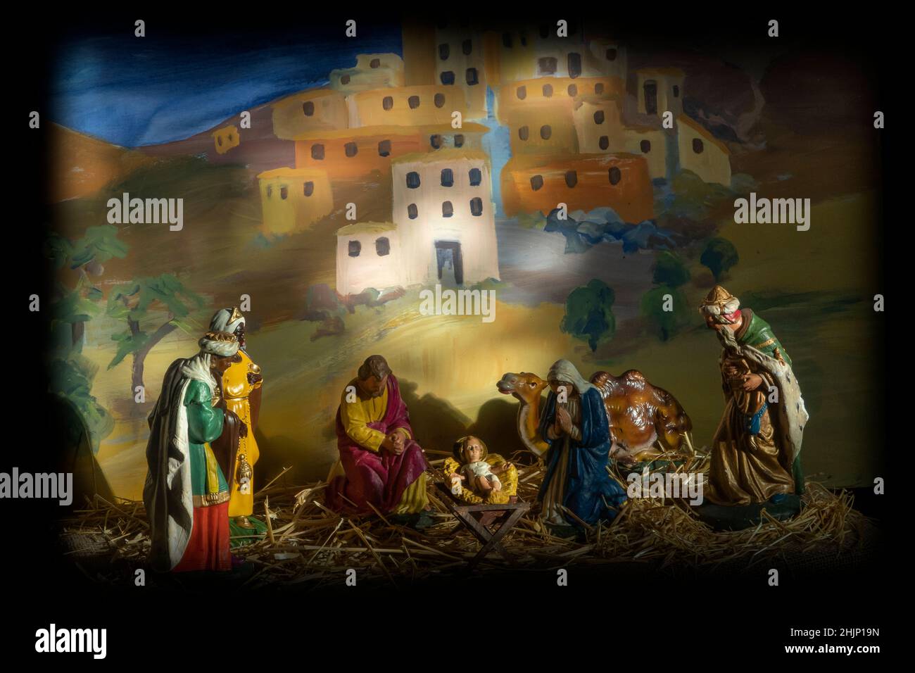 A nativity scene created with model figures on straw against a pained ...