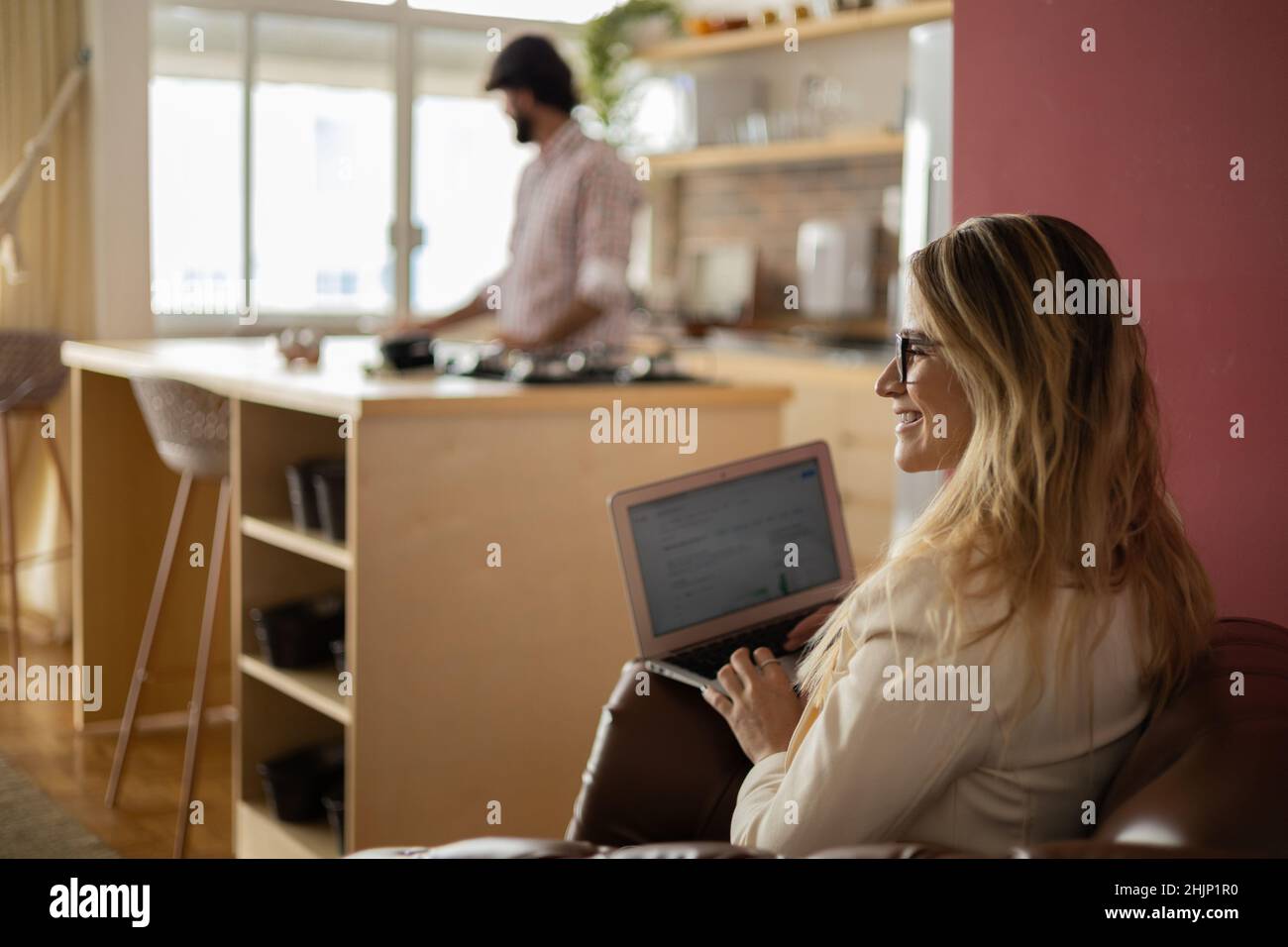 Young woman working at home with laptop and papers on desk and ...