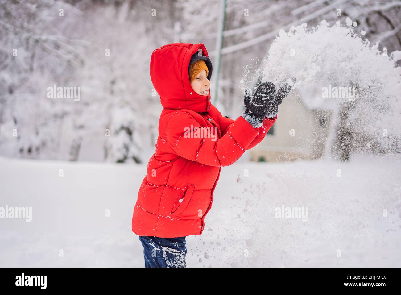 Funny little boy in blue winter clothes walks during a snowfall ...
