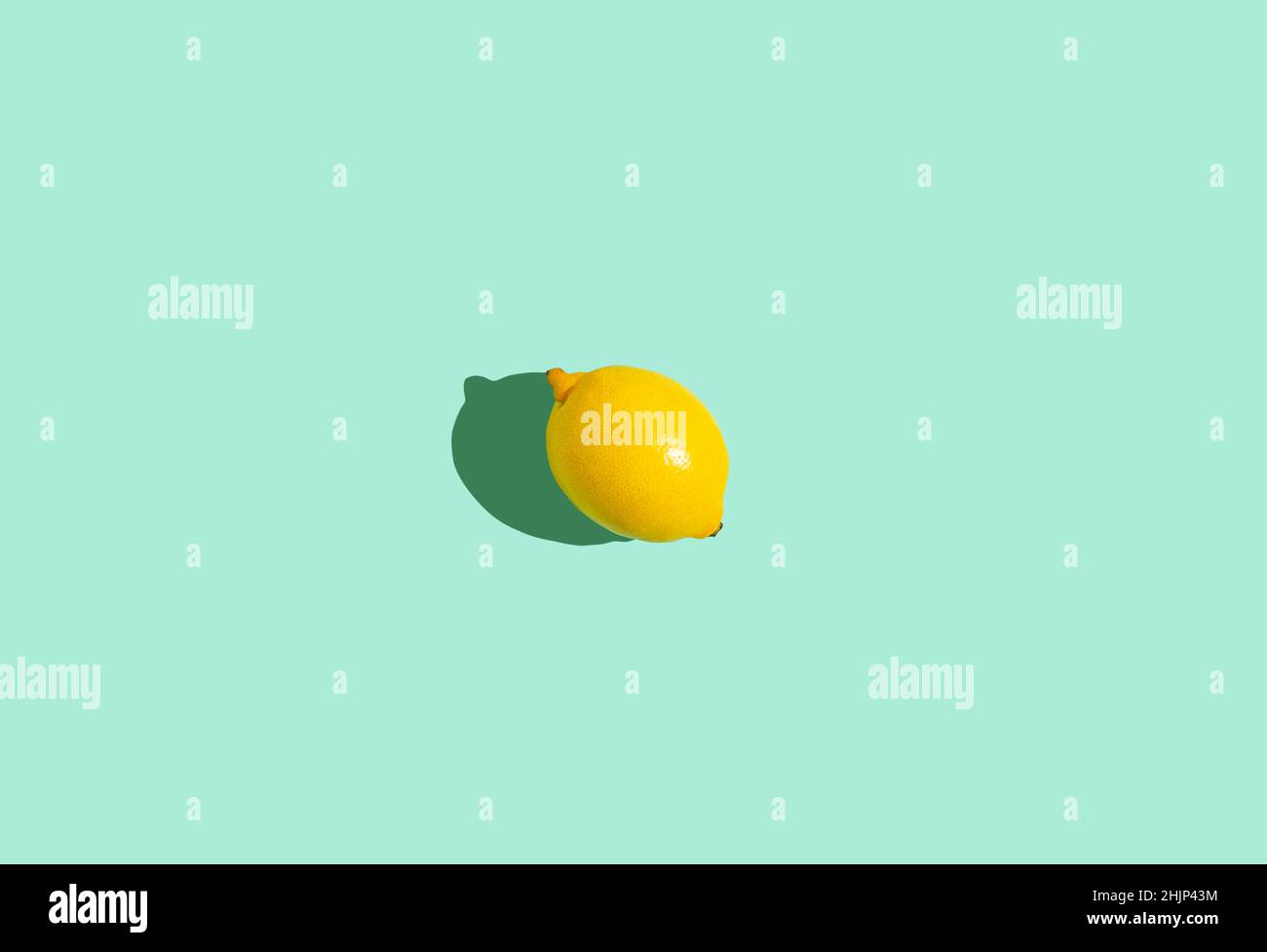 yellow whole one lemon in center of minimal blue background on bright ...