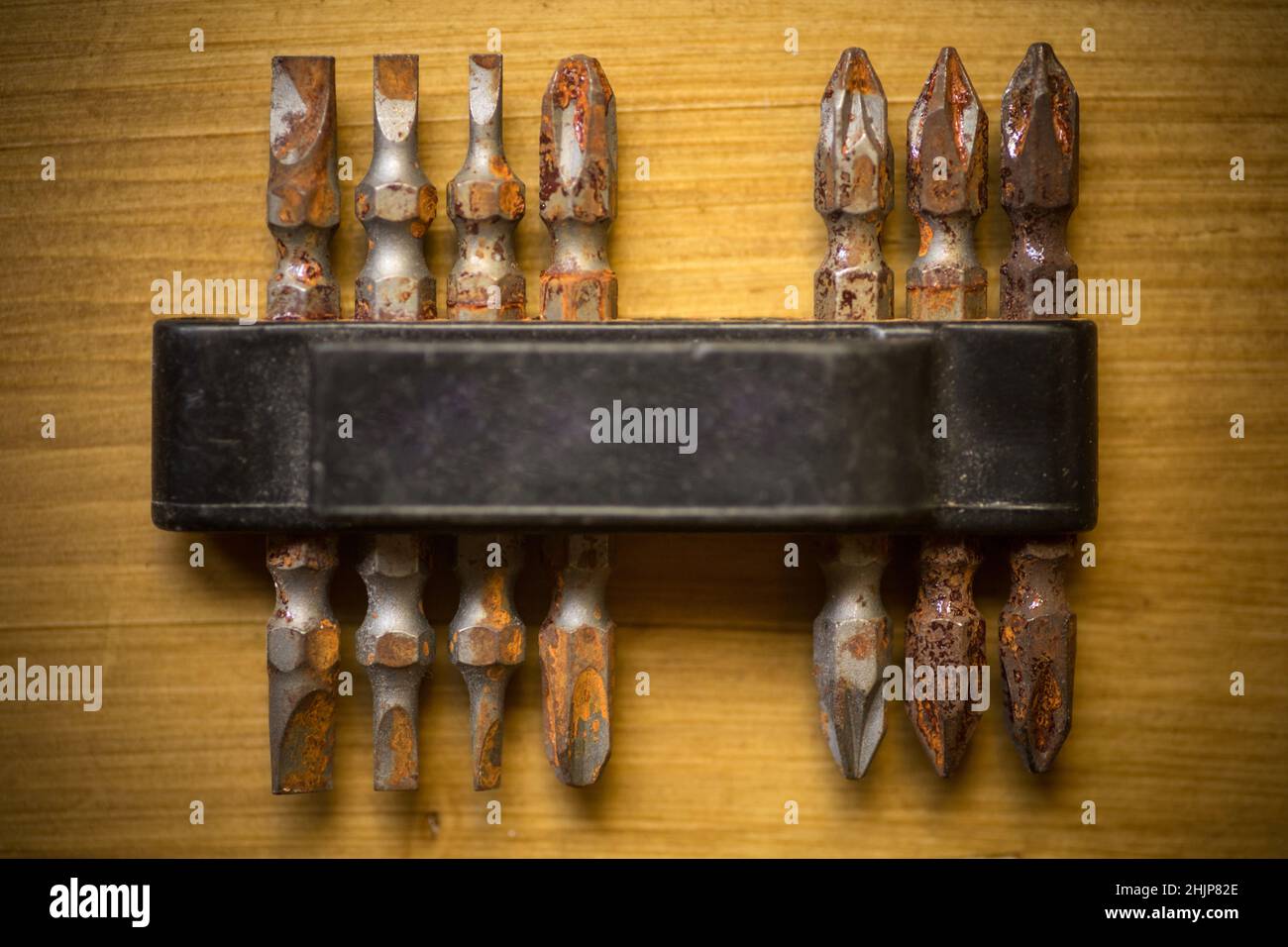 Close up shot of some used rusty screwdriver heads and bits on a wooden ...