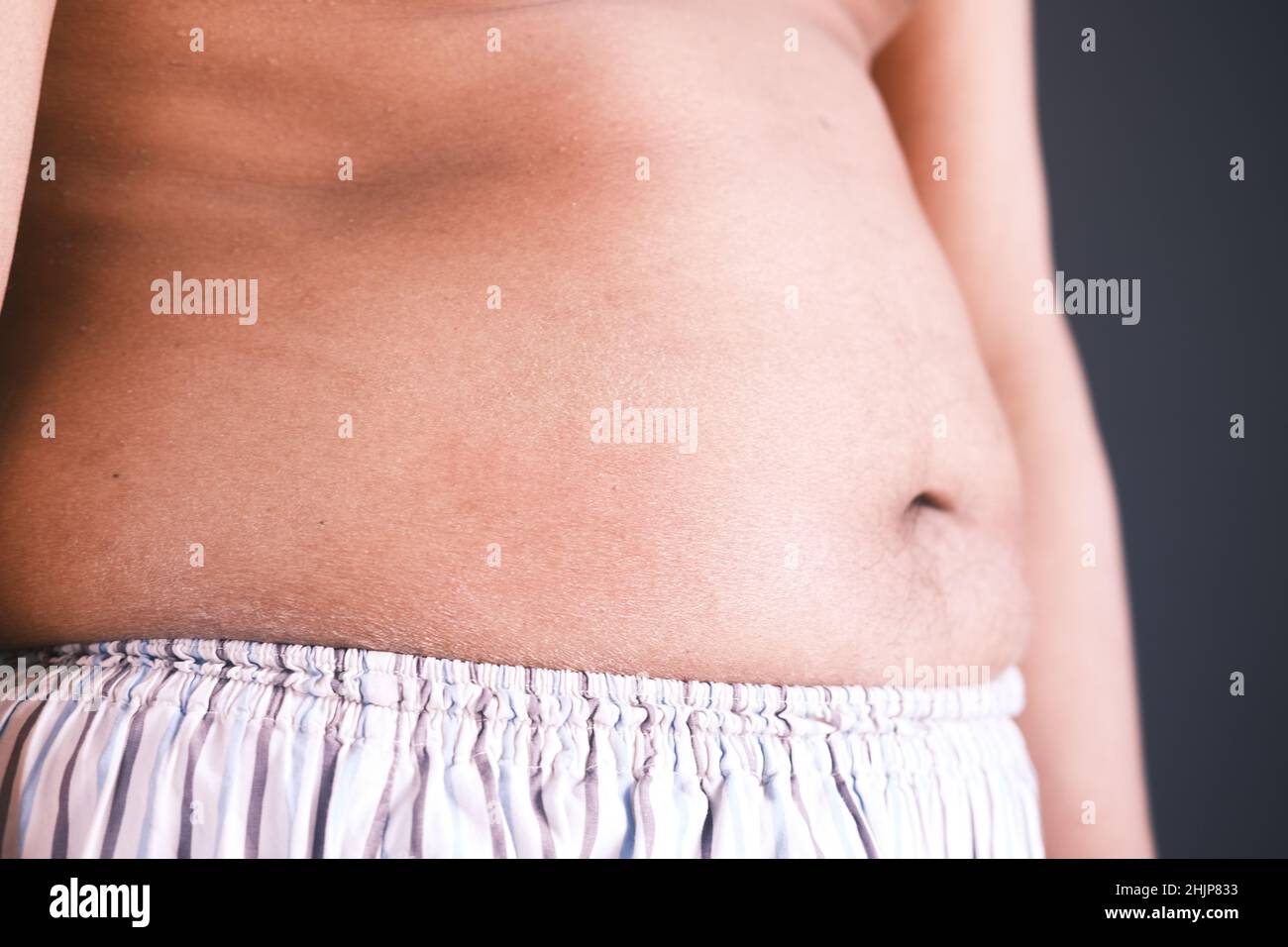fat man with a big belly against yellow background Stock Photo - Alamy