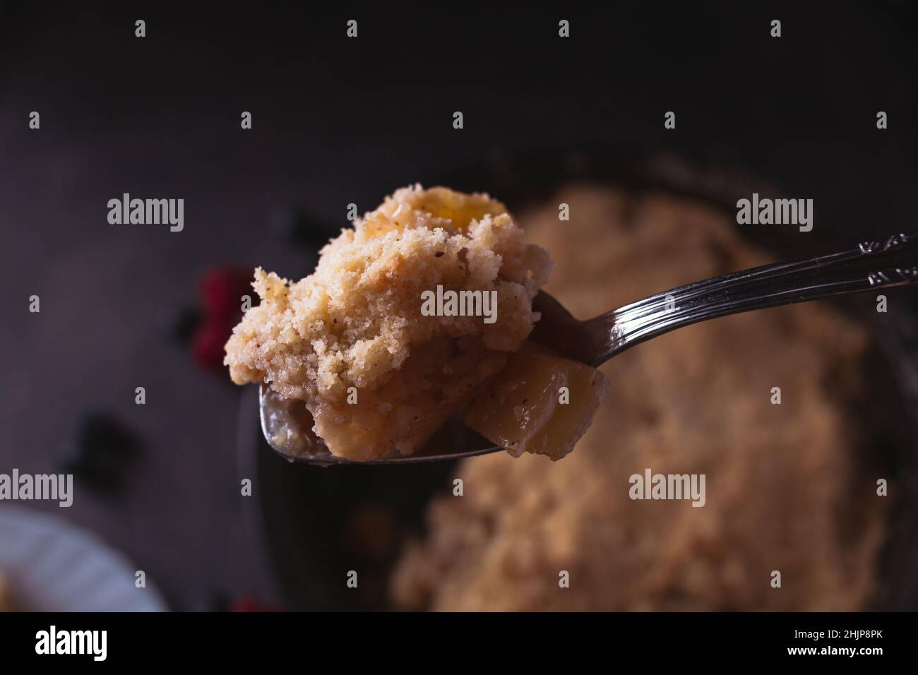 Spoon showing a piece of homemade apple crumble in low light. Dark food ...
