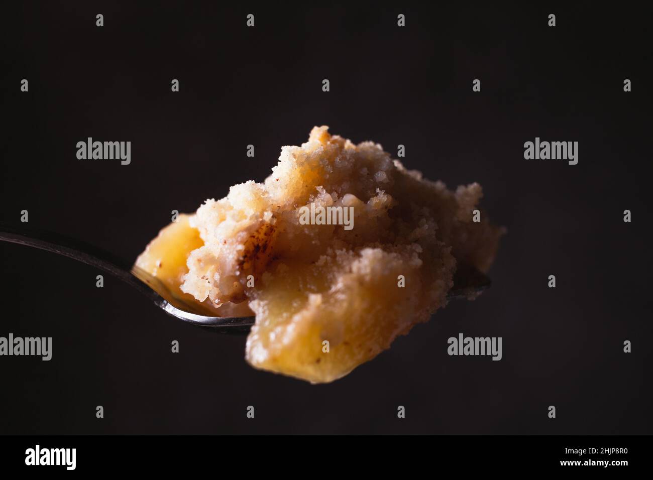 Spoon showing a piece of homemade apple crumble in low light. Dark food ...