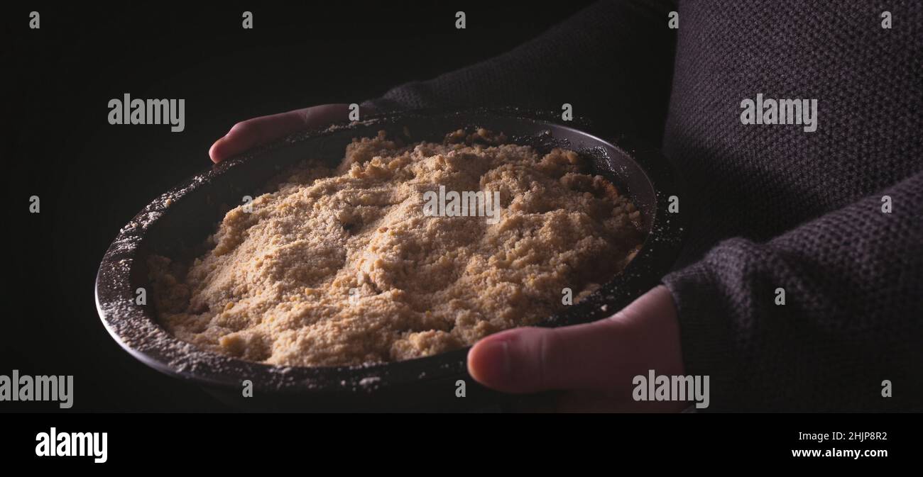 Hands showing homemade apple crumble in low light. Dark food photo with ...