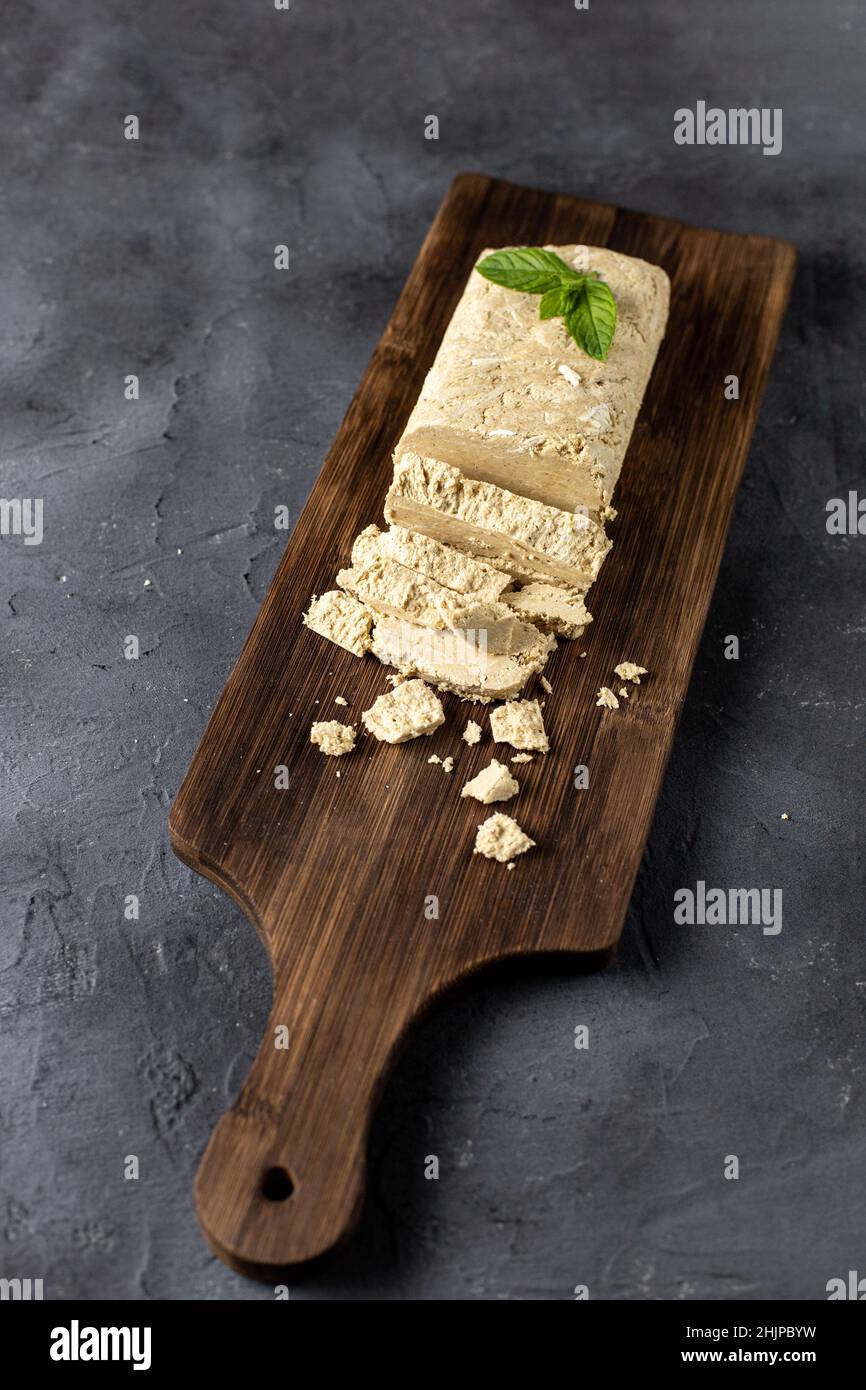 Slices of halva on cutting board. Sweet Turkish dessert with mint leaves on black background ...