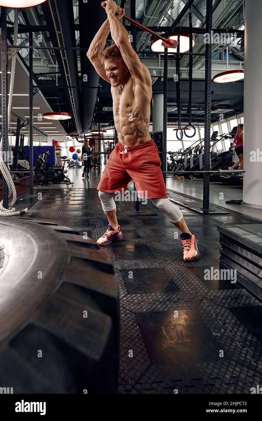Strength concept. Male athlete using hammer during fitness workout ...