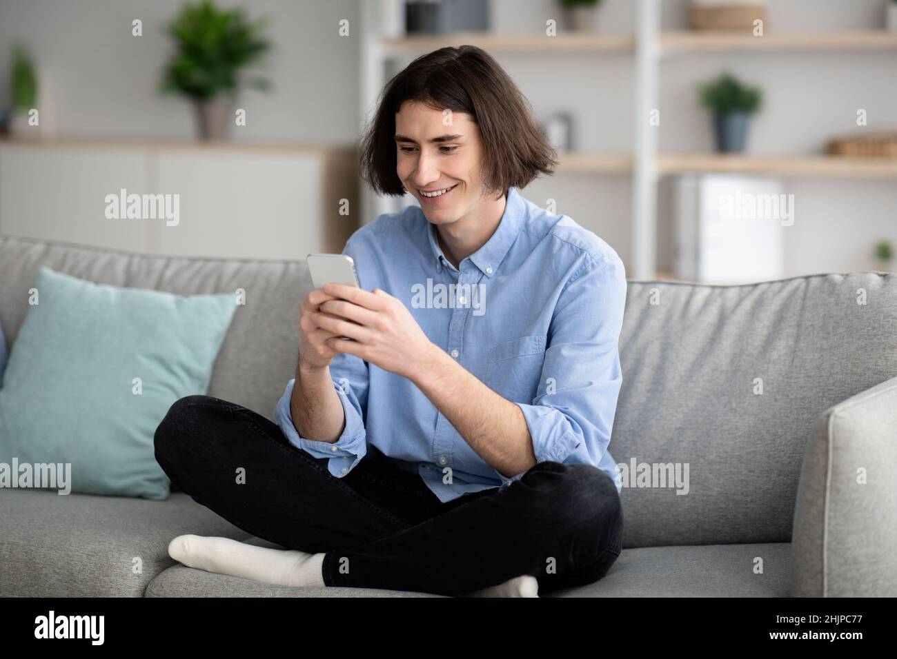 New mobile app. Happy young guy using smartphone, texting and browsing ...