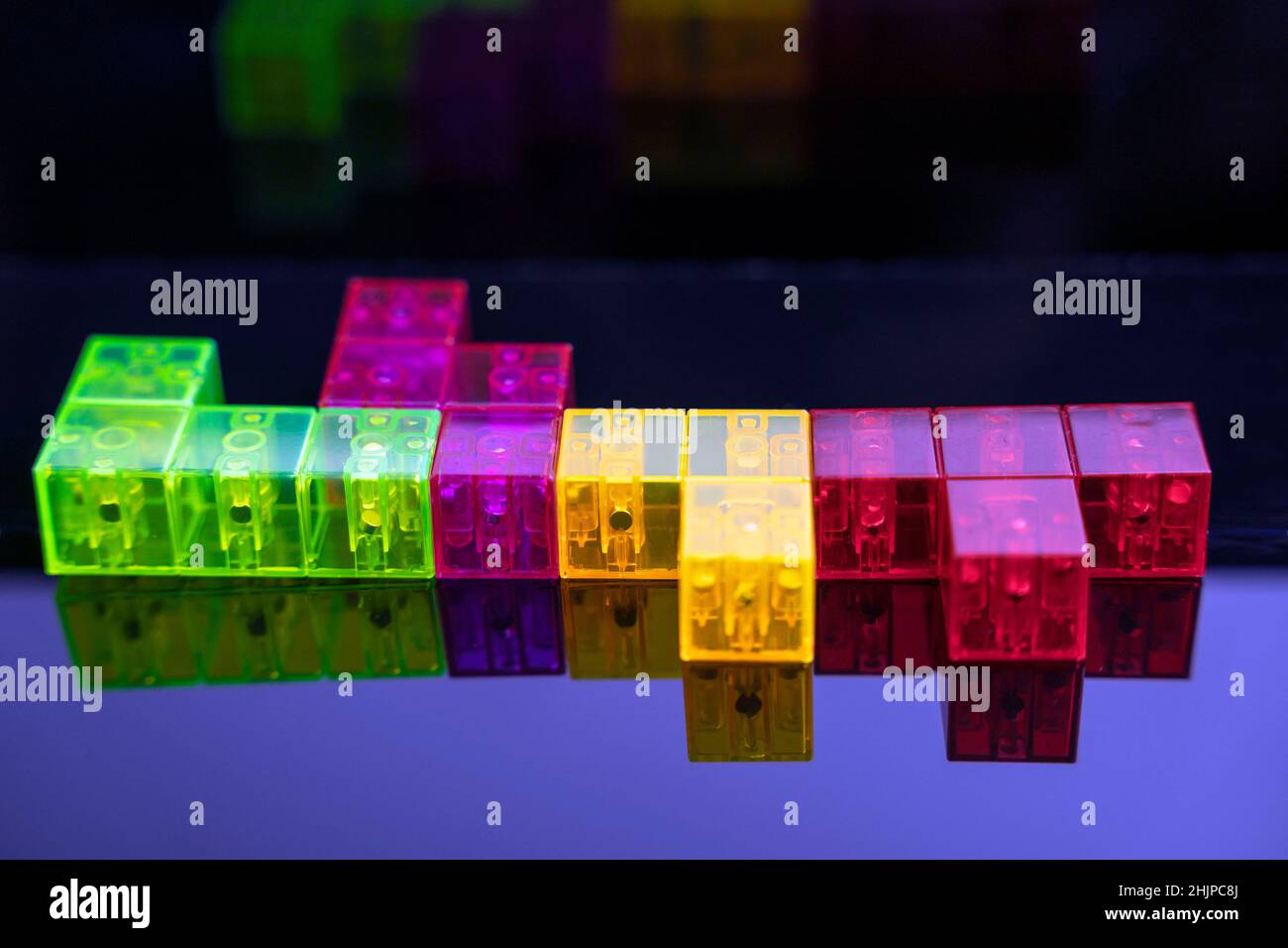 three-dimensional colored tetris figures on glossy black glass, space ...